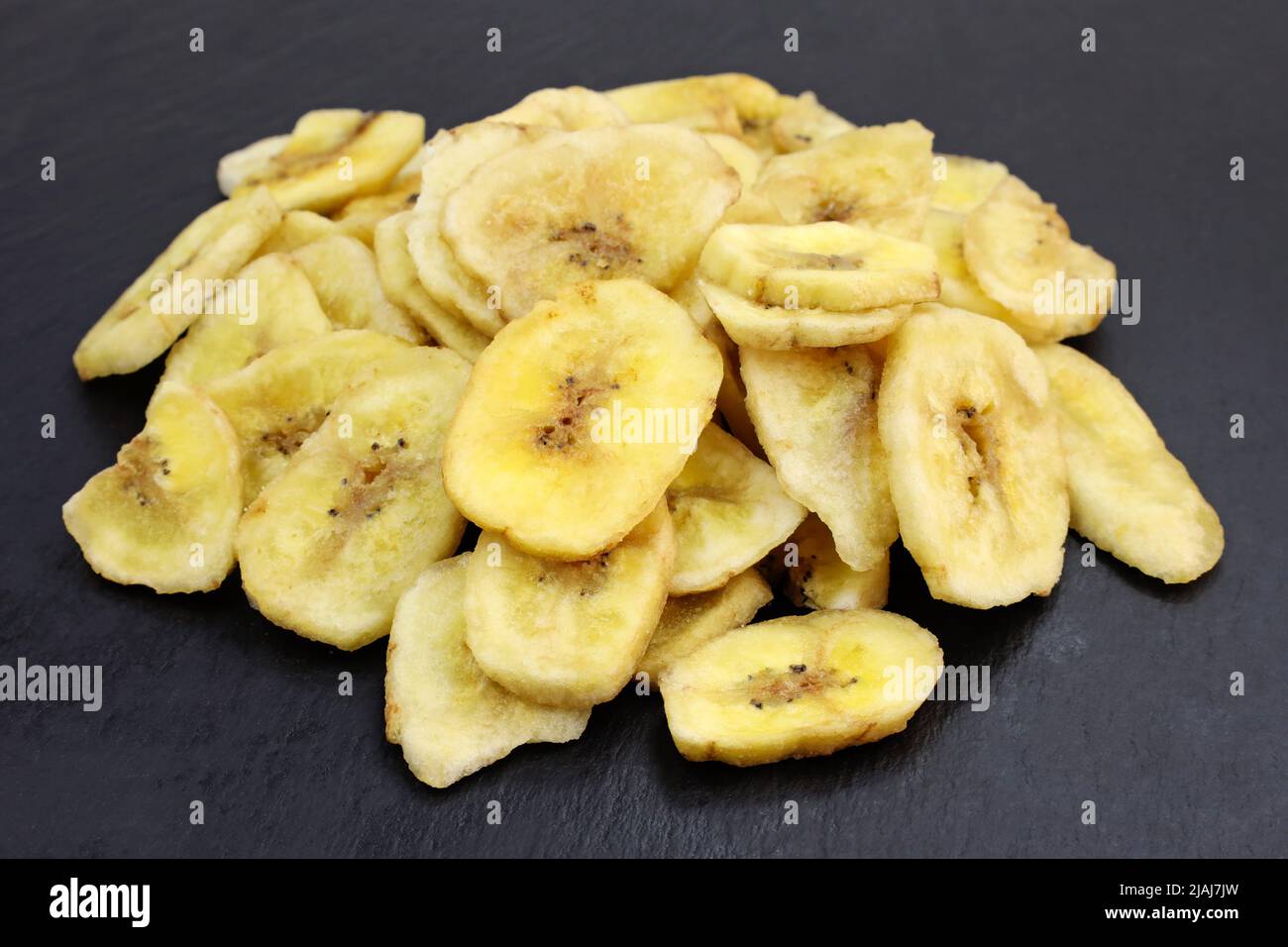 Heap of dried bananas on the black background. Sweet snacks Dried ...