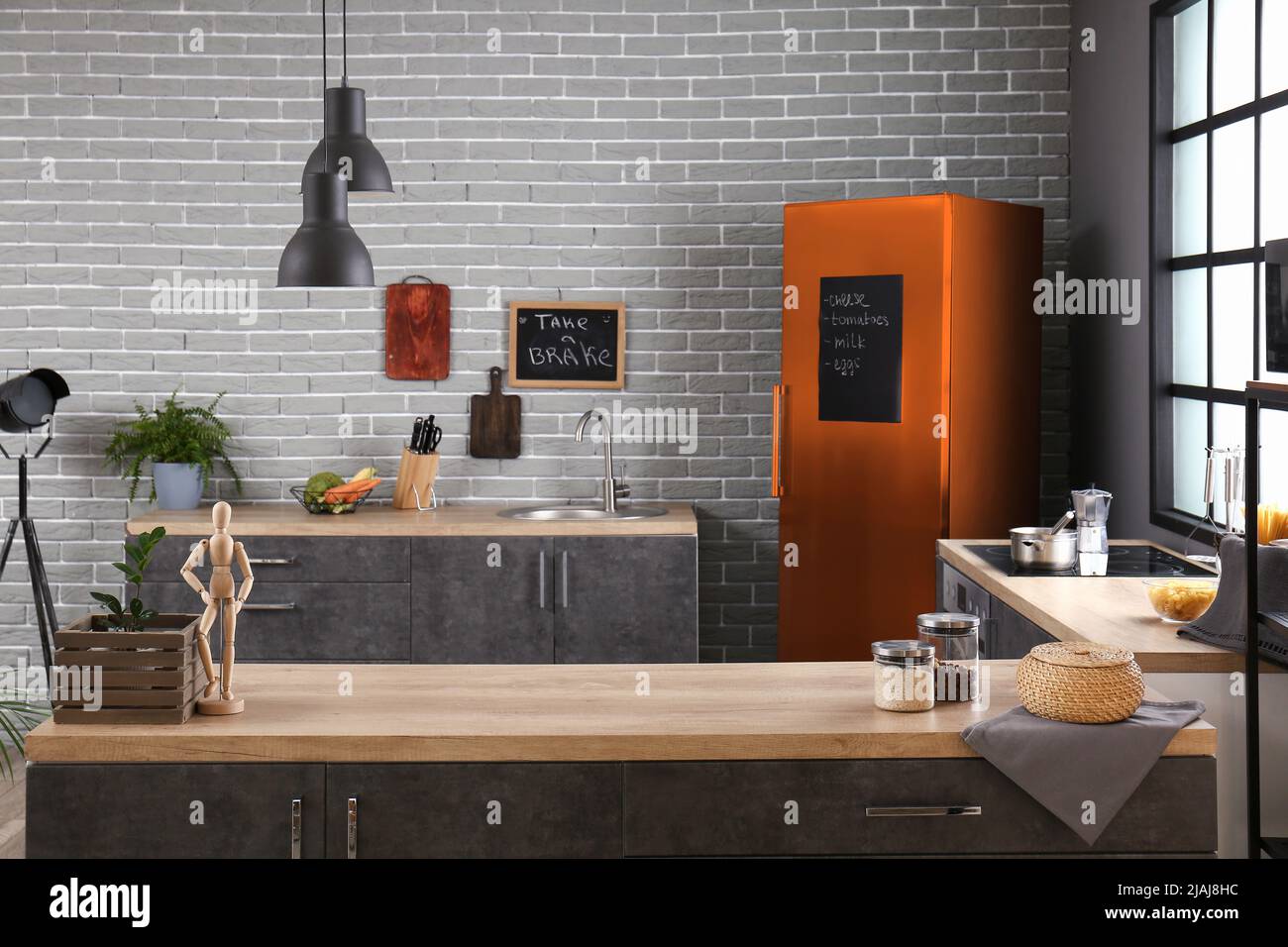 Interior of modern comfortable kitchen with orange fridge near brick ...