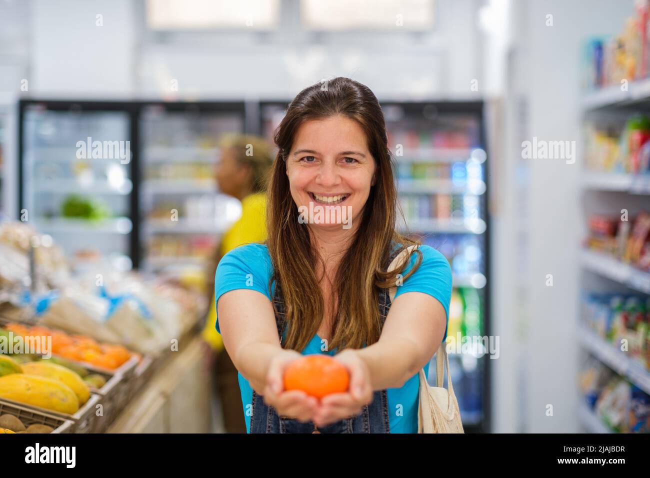 Middle aged woman grabbing an orange in market Stock Photo - Alamy