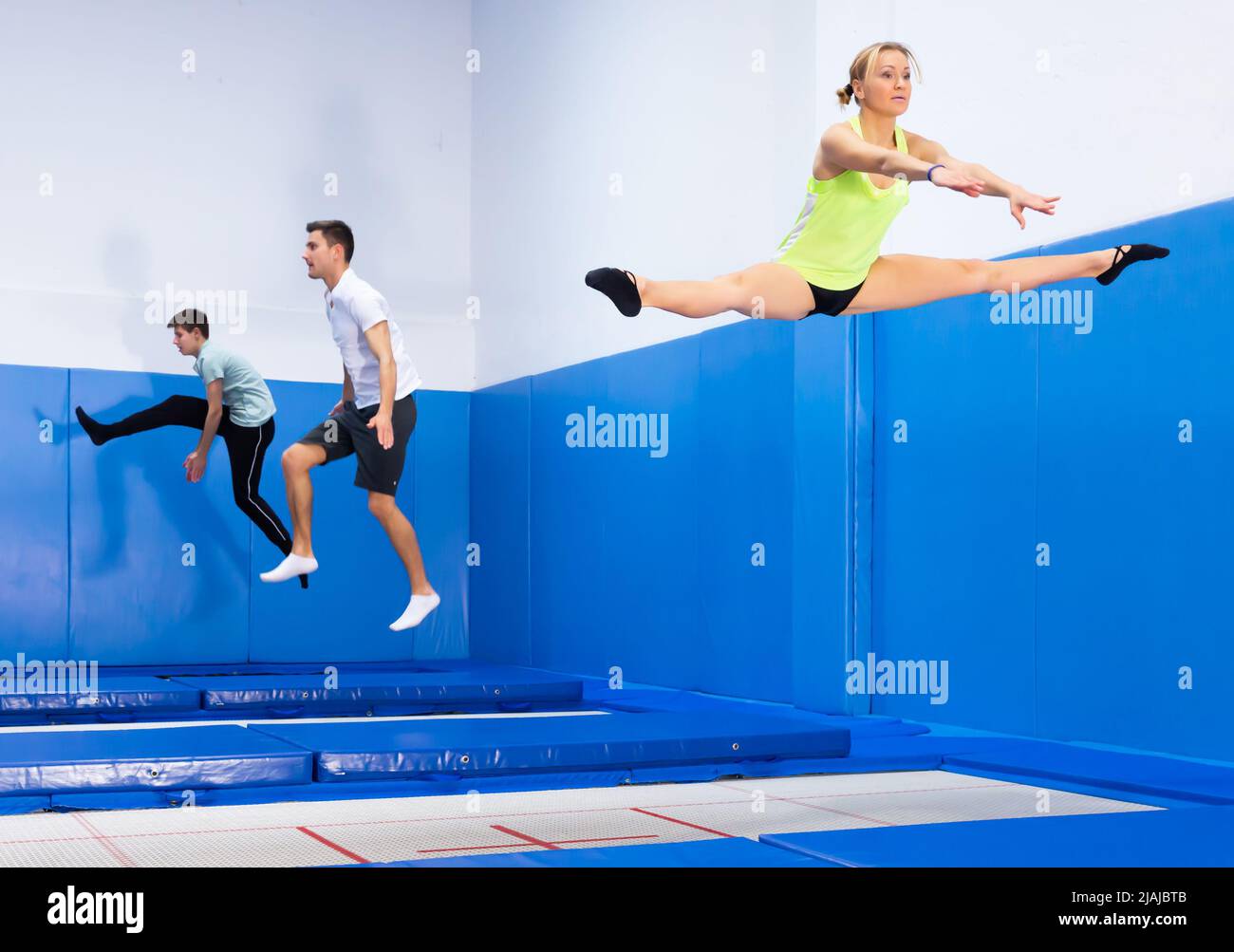 Female gymnast practicing middle split on trampoline Stock Photo - Alamy