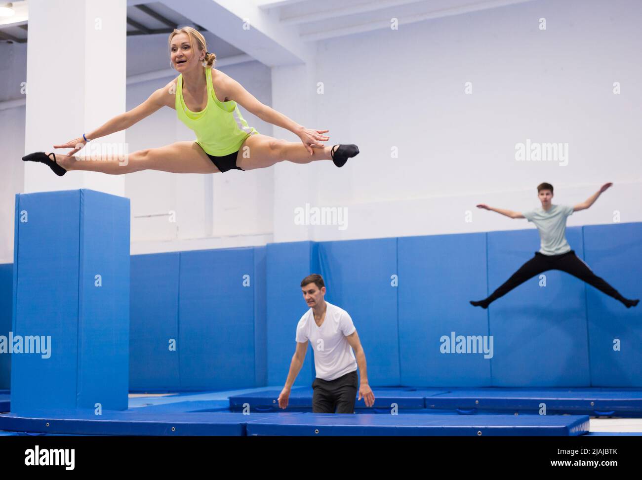 Female gymnast practicing middle split on trampoline Stock Photo - Alamy