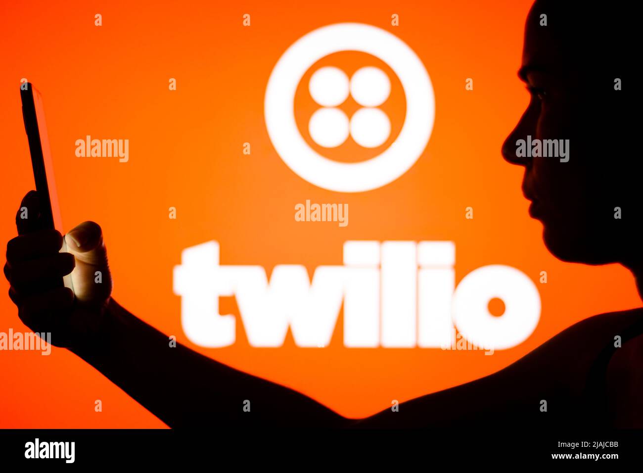In this photo illustration, the Twilio logo is seen in the background of a silhouetted woman ...