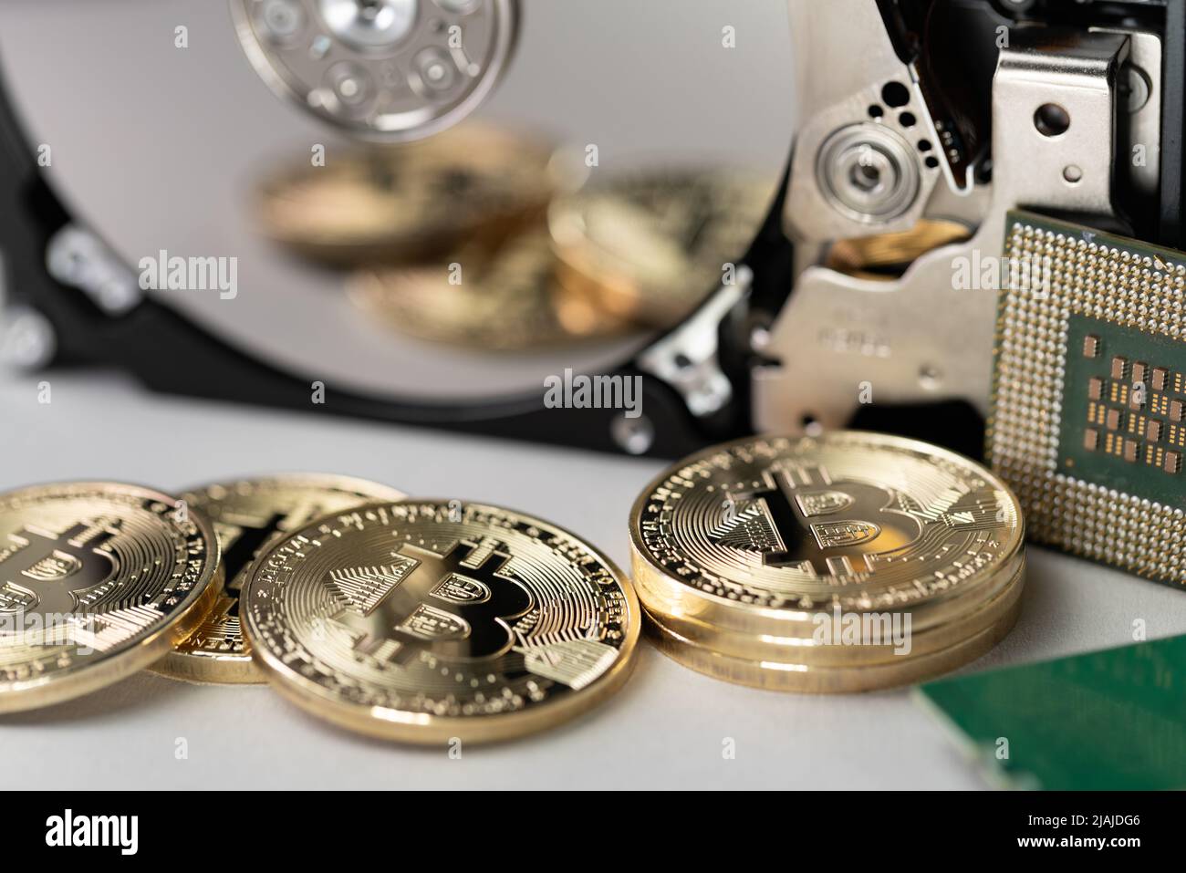 Bitcoin coins next to hard drive and microprocessor. Coins reflecting ...