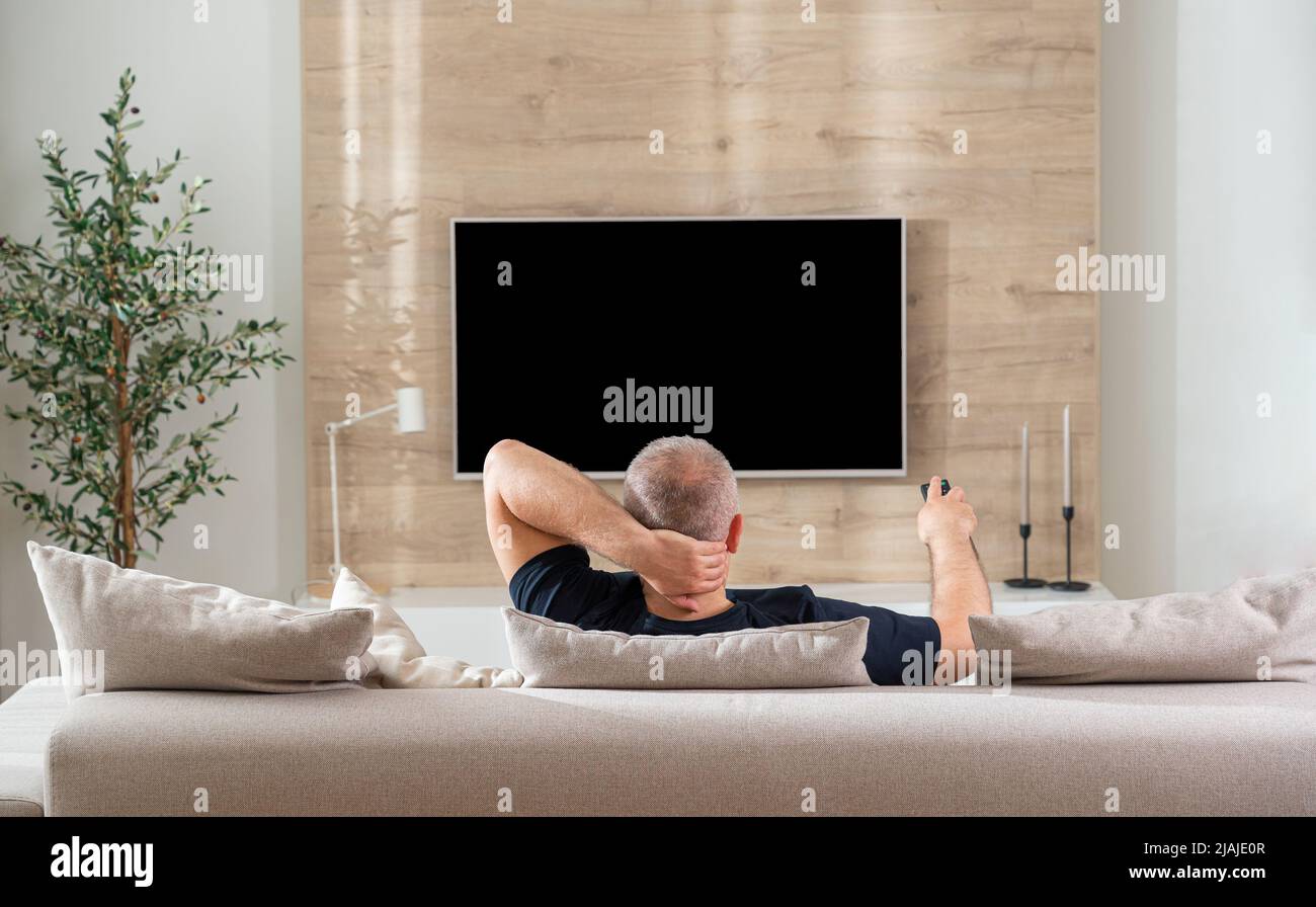 man sitting on sofa in modern living room back view Stock Photo - Alamy