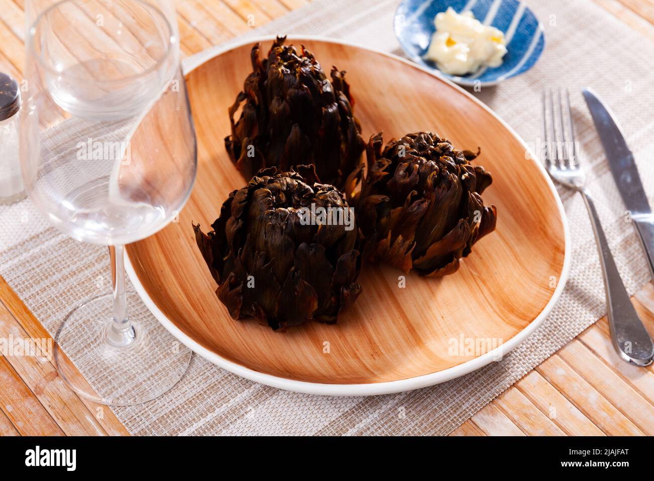 Tasty whole roasted artichokes served on plate Stock Photo - Alamy