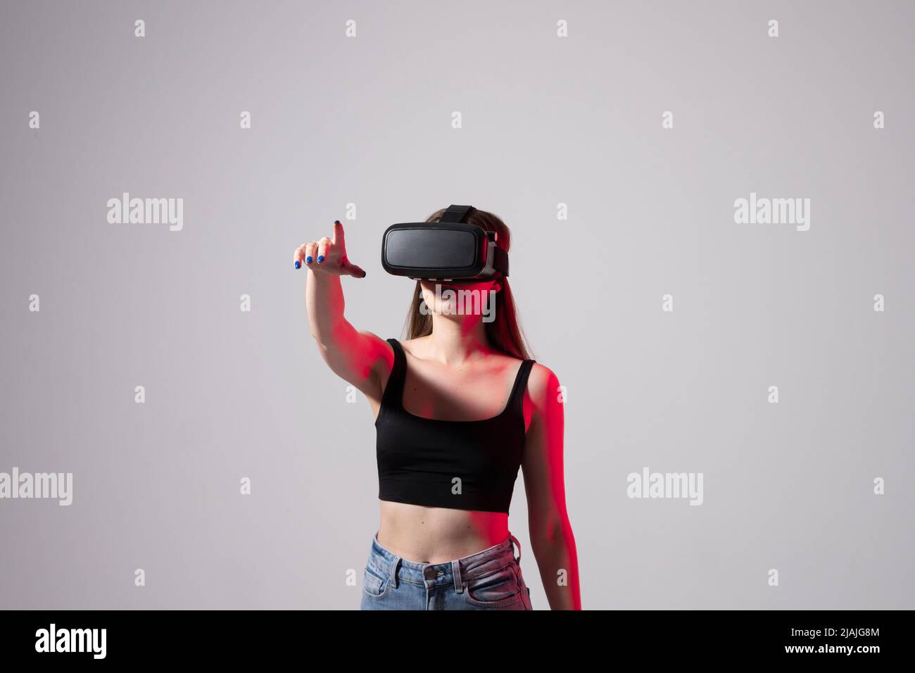 Young woman working in VR goggles on a grey background. Modern architect using virtual reality ...
