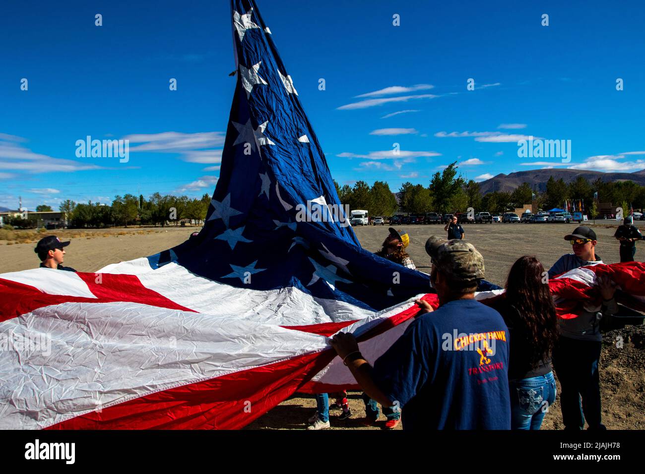 People hold a flag up before it was raised by a crane. People attended ...