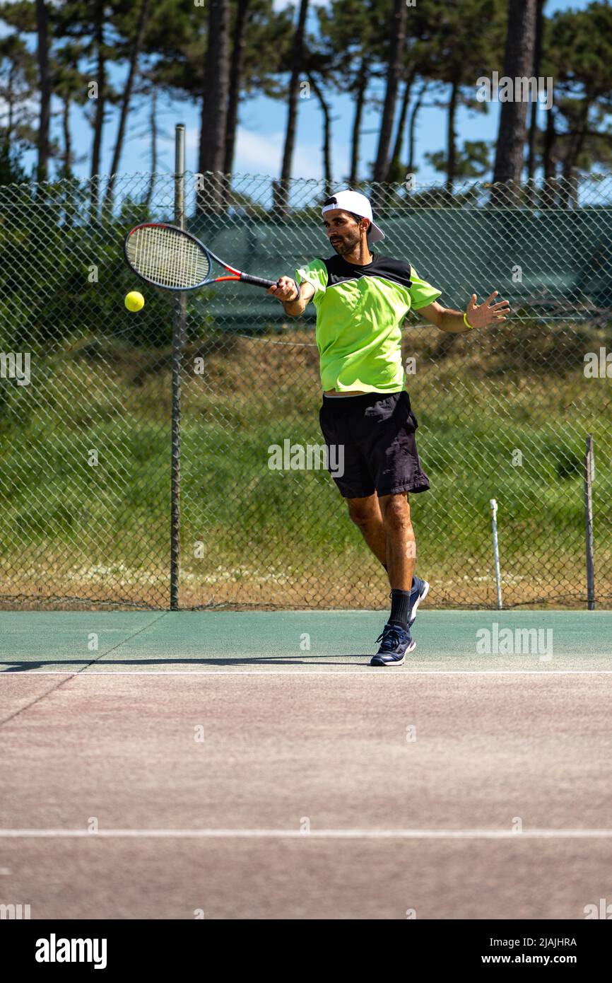 Tennis player hitting forehand at ball with racket on court Stock Photo ...