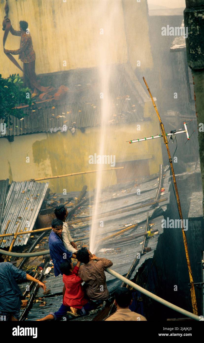 People try to hose down an accidental fire spread throughout a slum in ...
