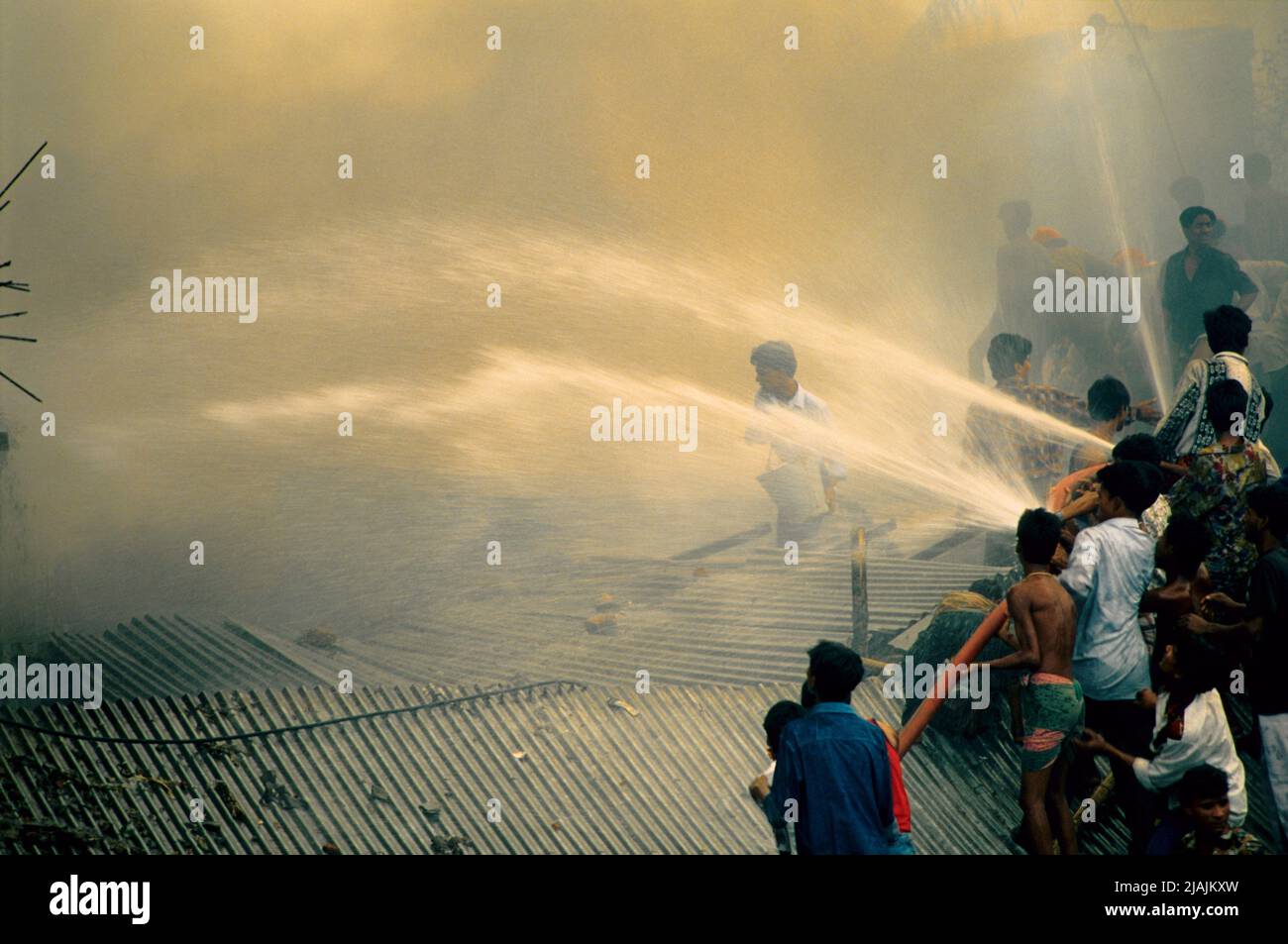 People try to hose down an accidental fire spread throughout a slum in ...