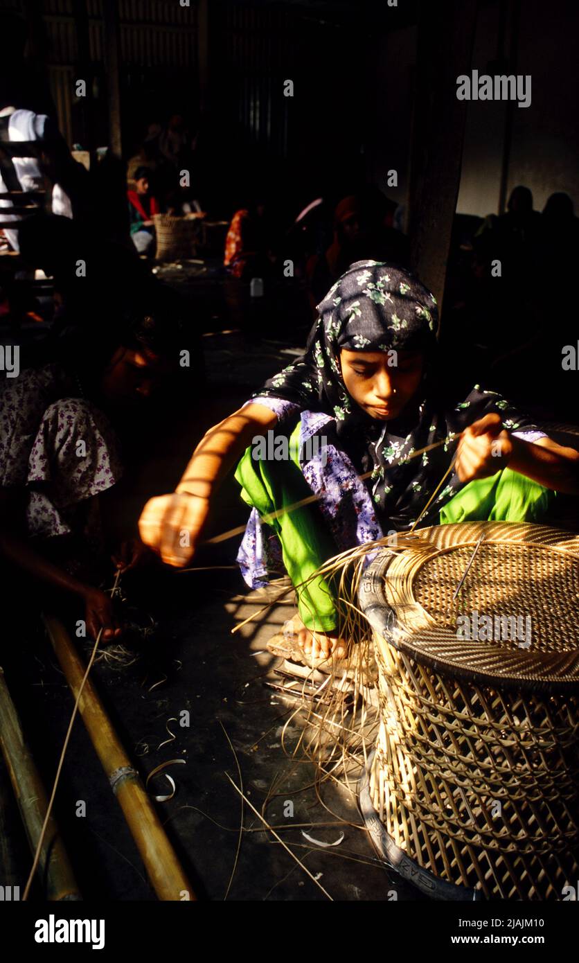 Rural woman weaving a sitting stool (mora) with bamboo. Netrokona ...