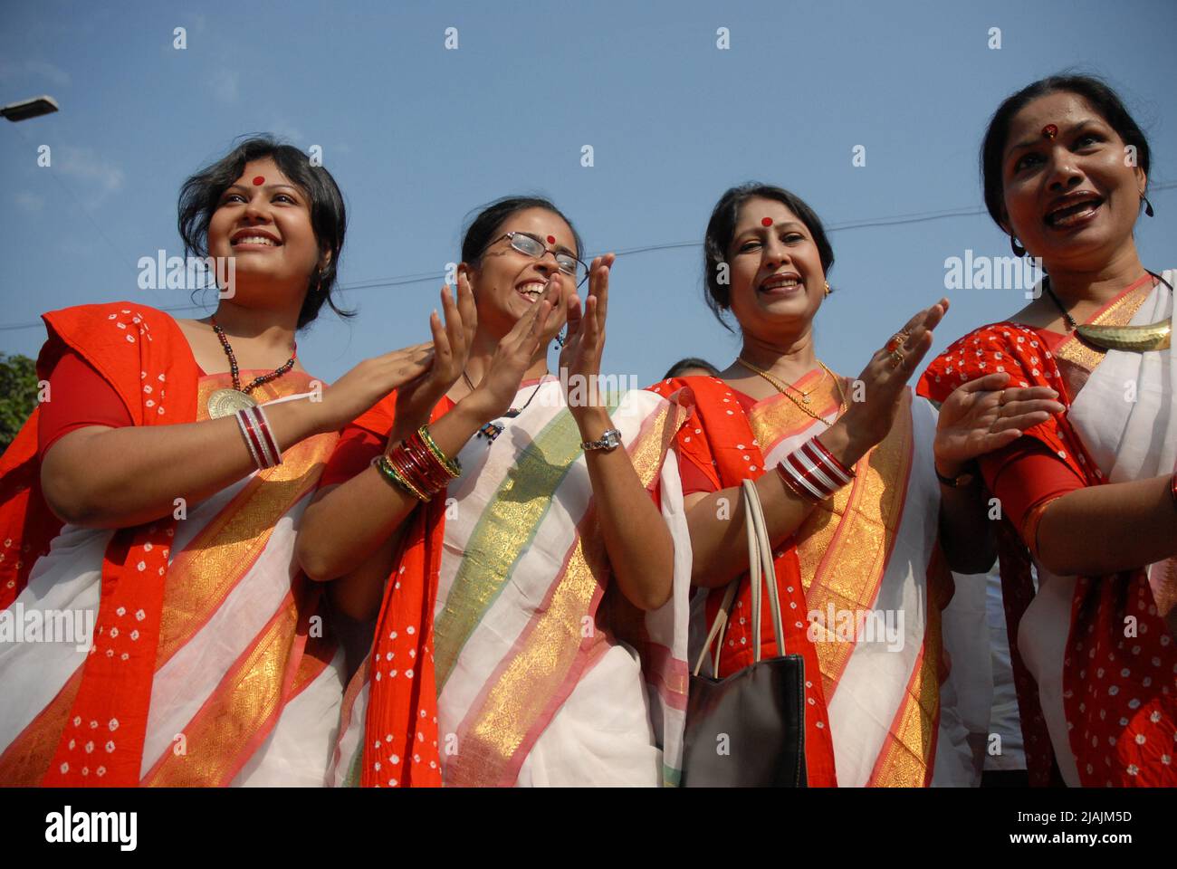 Dressed traditionally in saris, women sing to celebrate the occasion of ...