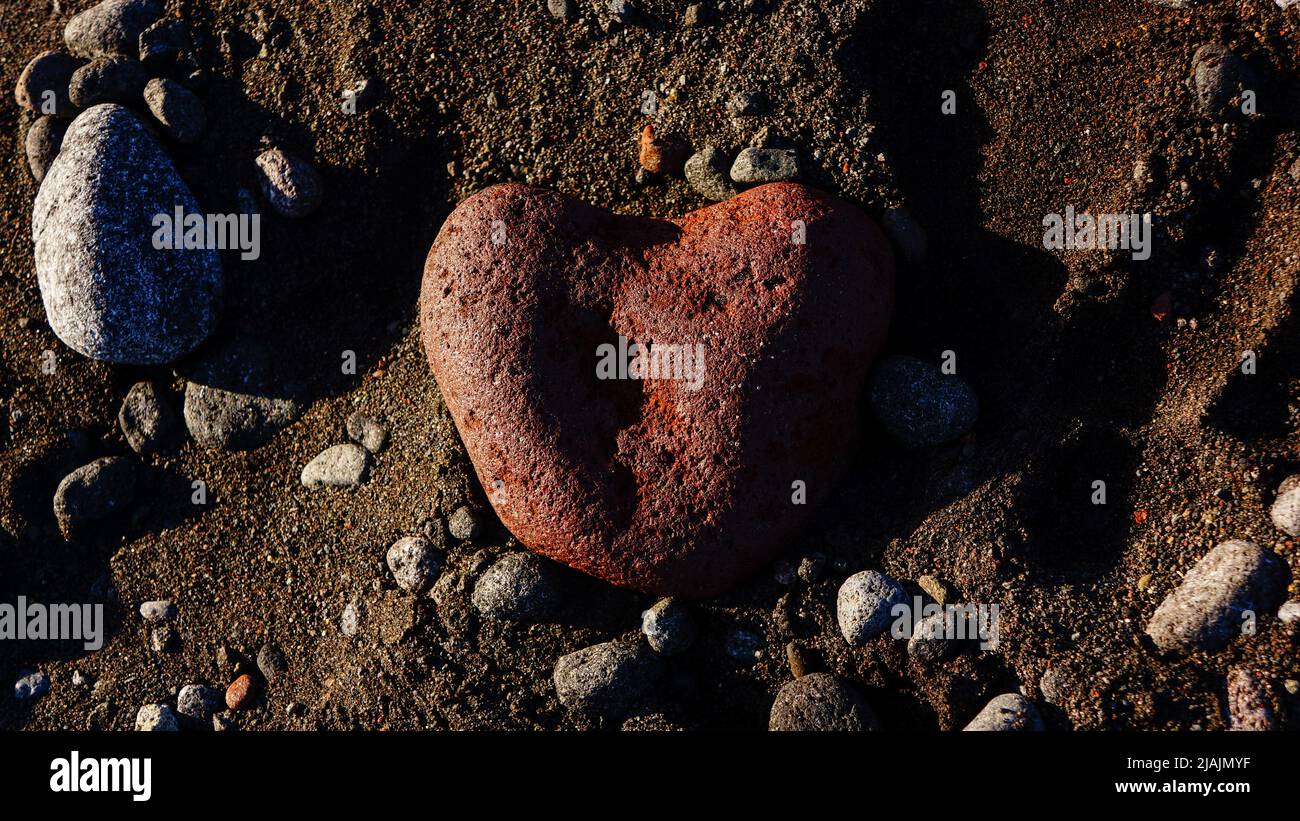 Heart shaped stone, red in color around pebbles and other stones Stock ...