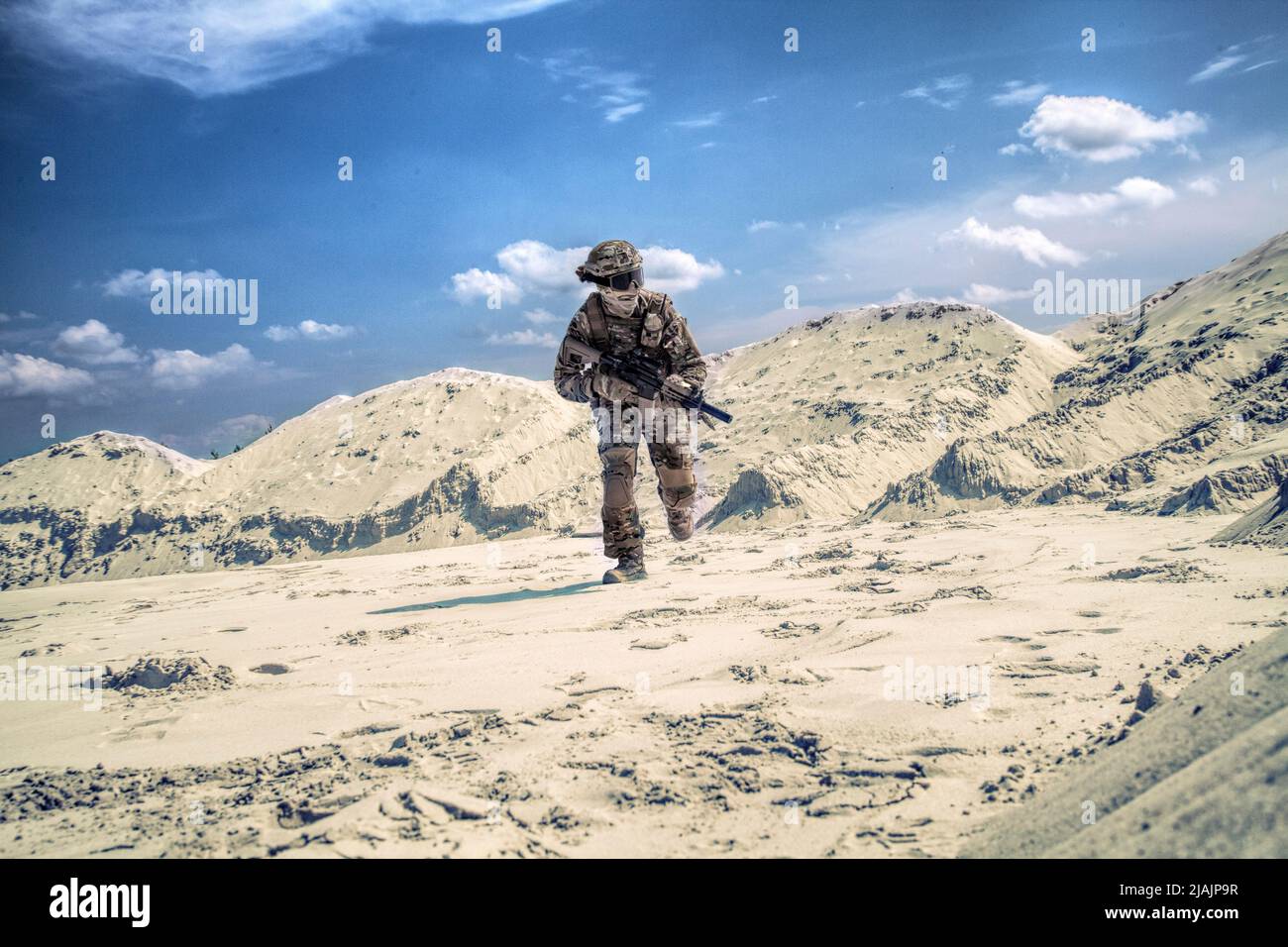 Man in military camouflage uniform running over a desert area during ...