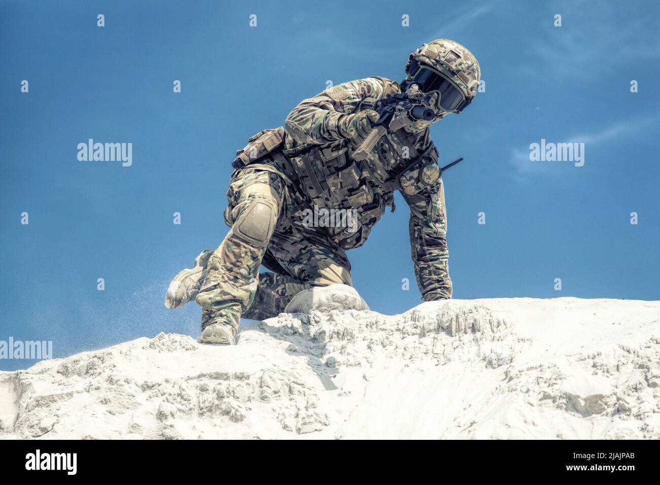 Serviceman jumping over sand dune and shooting weapon Stock Photo - Alamy