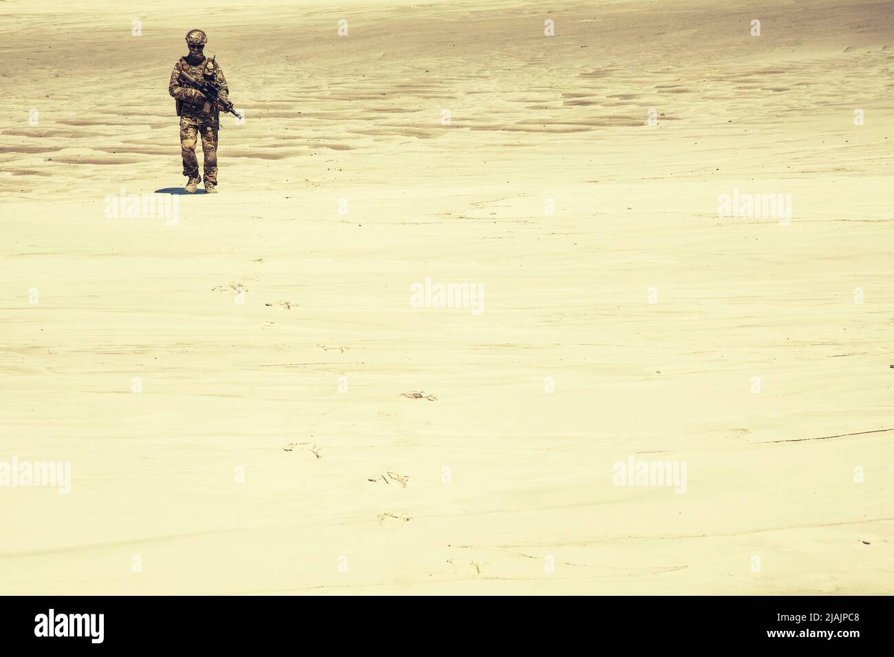 Desaturated photo of a lone Army soldier walking through a hot desert ...