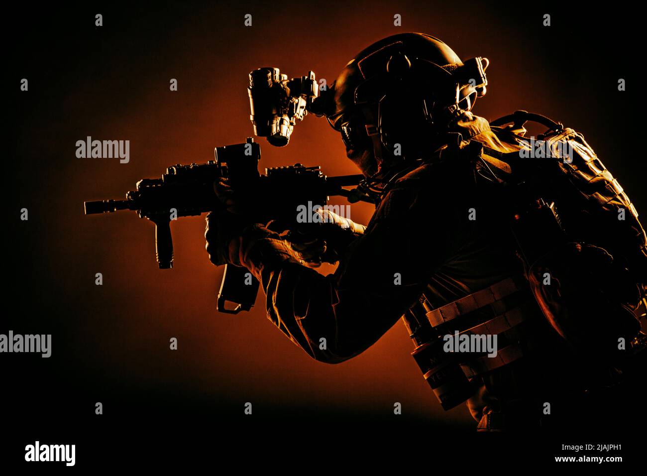 A special operations soldier wearing night vision device, aiming short ...