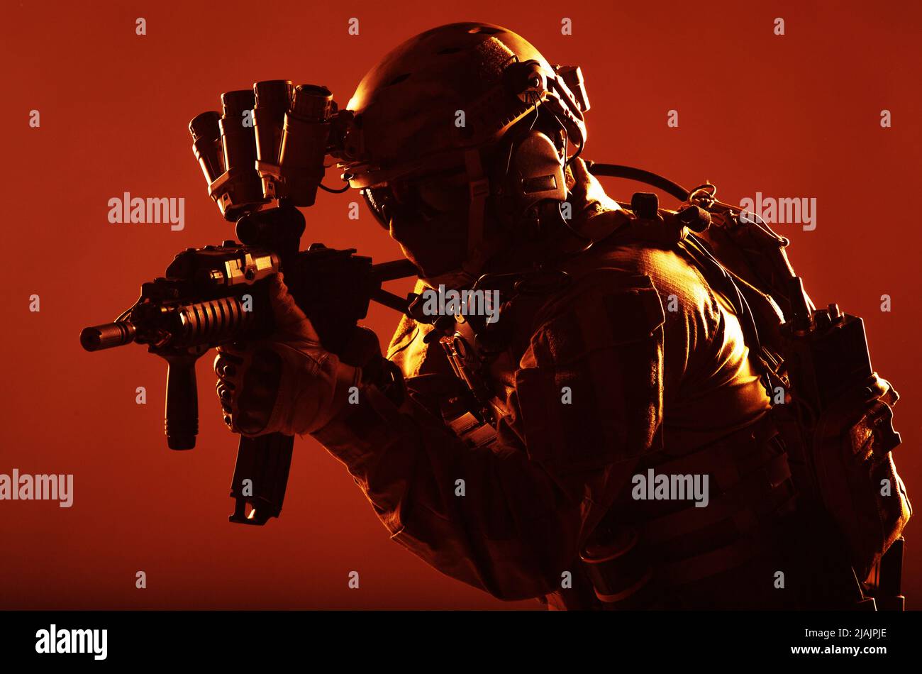 A special operations soldier wearing night vision device, aiming short ...