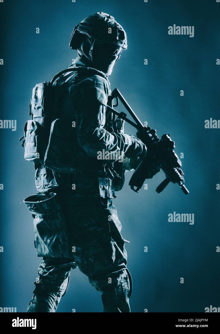 Army soldier in battle uniform with service rifle in hand, looking back ...