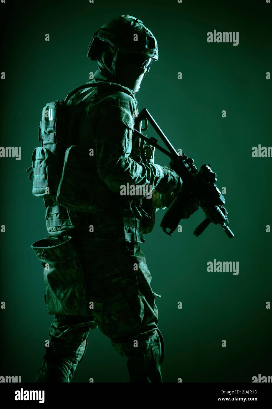 Army soldier in battle uniform with service rifle in hand, looking back ...