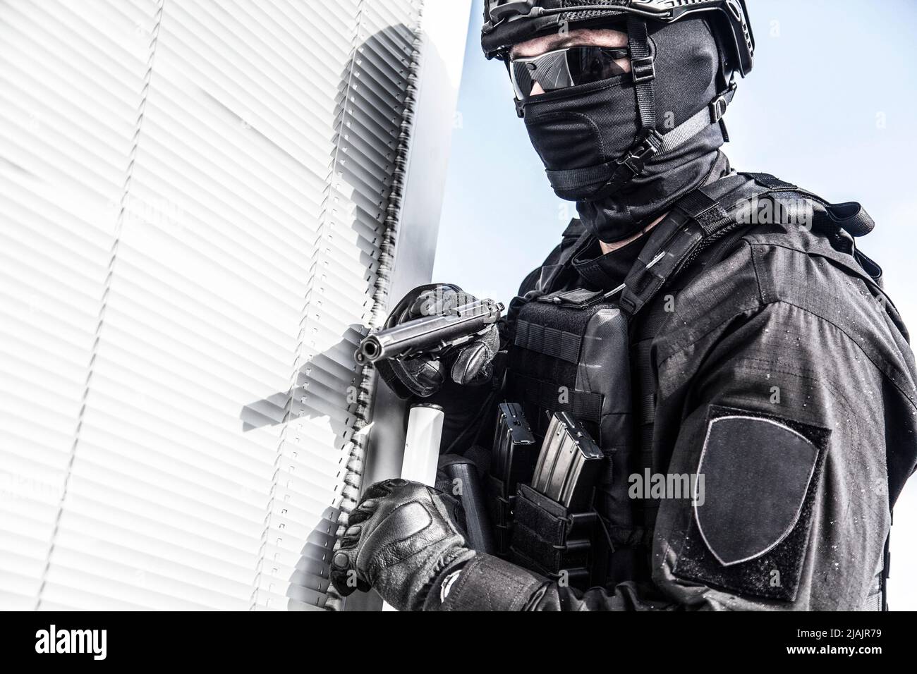 SWAT team member armed with pistol, grabs a door handle before breaking ...