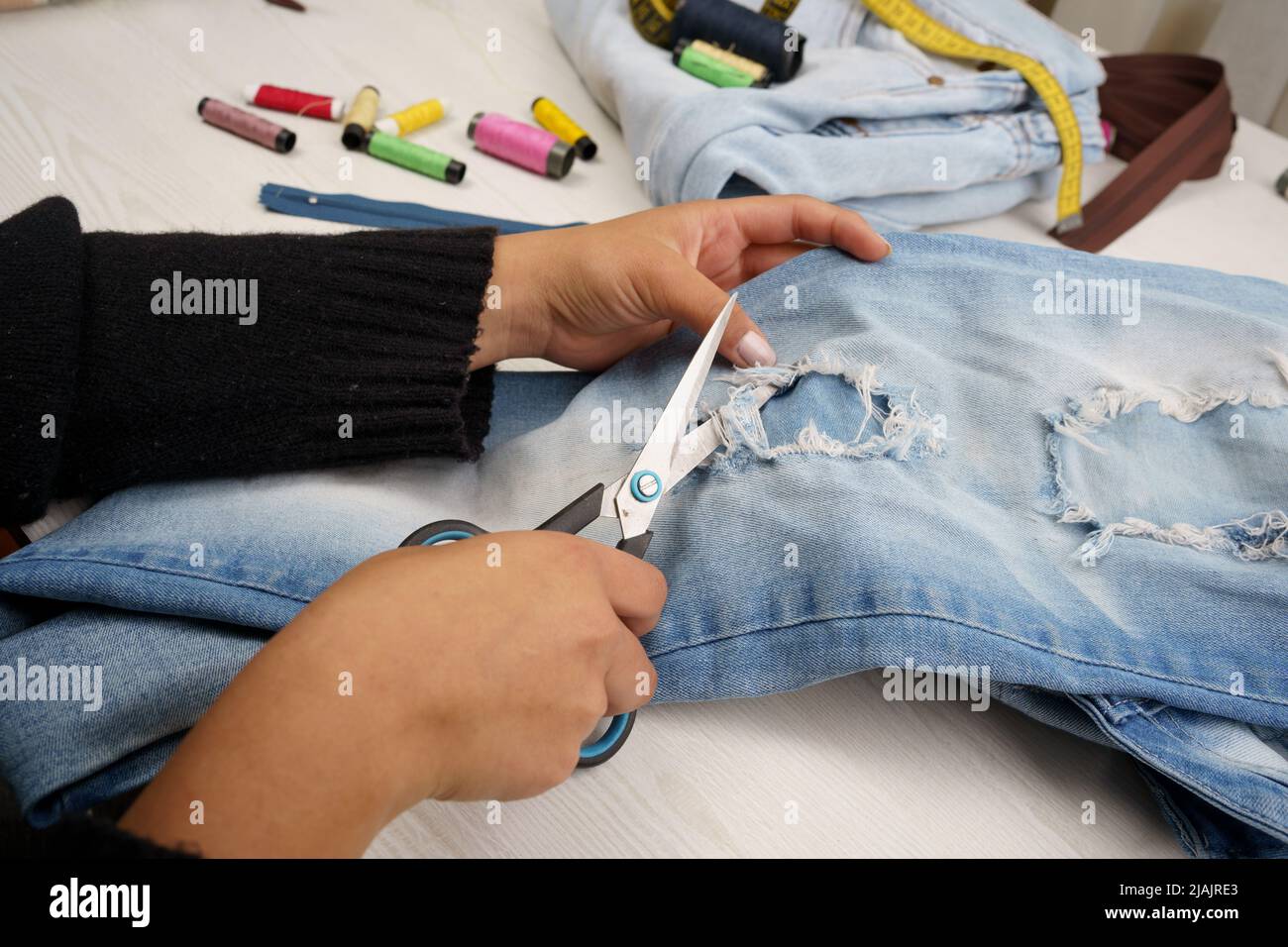 repairing garment, cutting with scissors in textile, dressmaker working ...