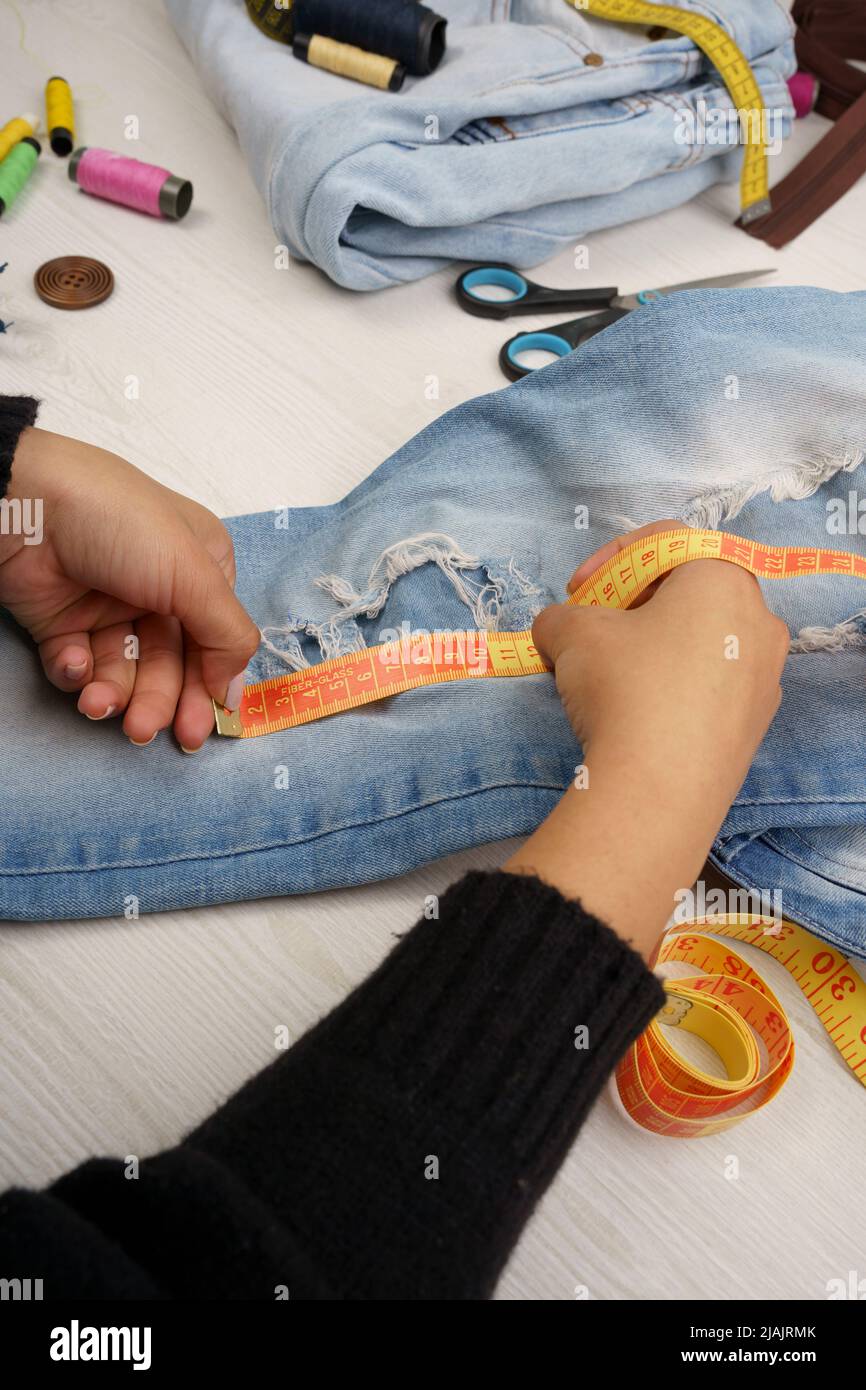 measuring jean pants with tape measure, work table with sewing ...