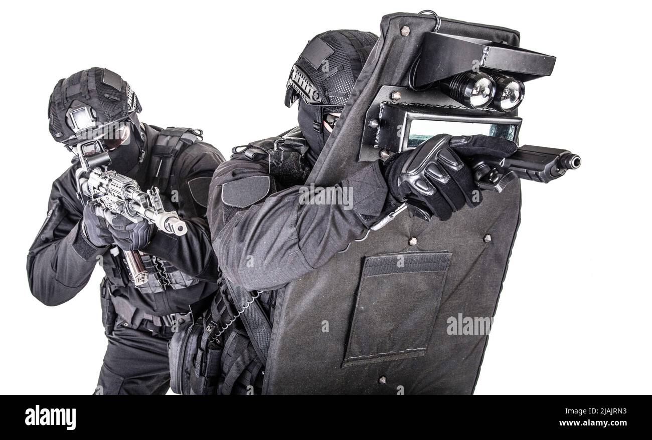 SWAT team members aiming with pistol and assault rifle behind ballistic ...