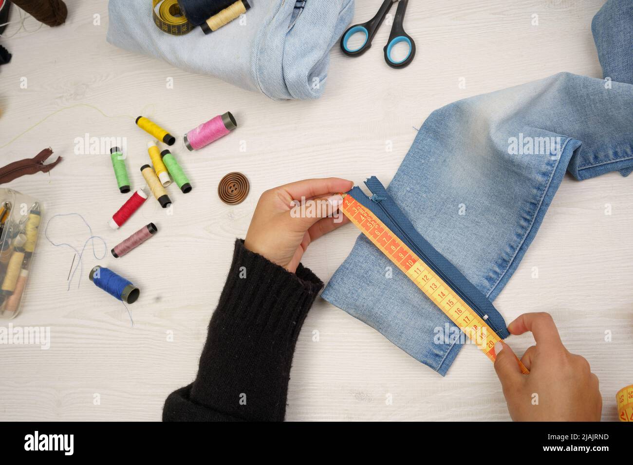 work table in a sewing workshop, measuring the hem of a pair of pants ...