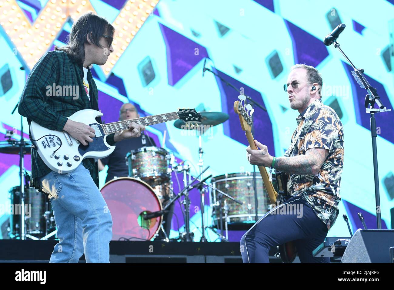 Musicians Rivers Cuomo and Scott Shriner are shown performing on stage ...