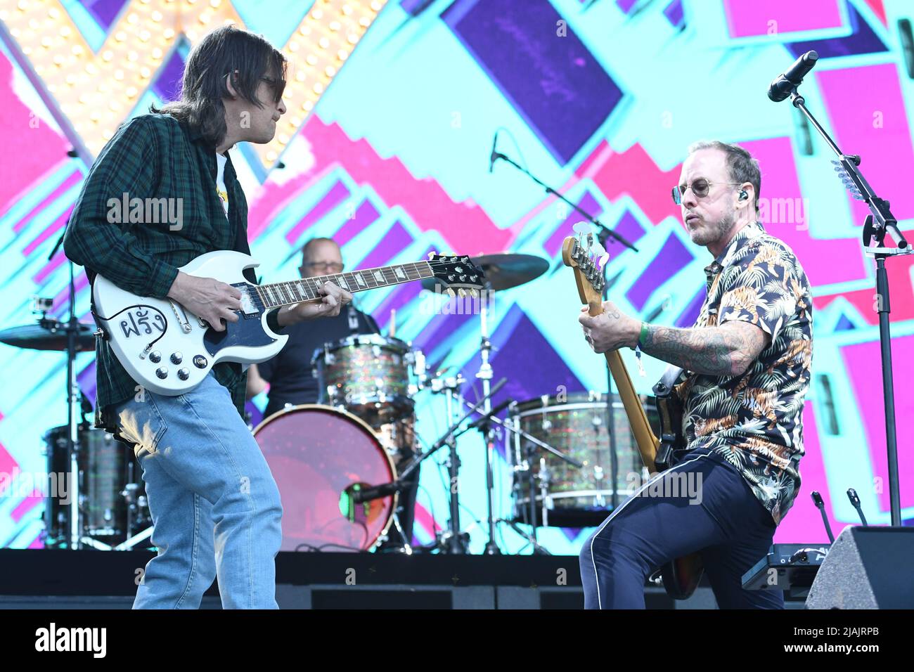 Musicians Rivers Cuomo and Scott Shriner are shown performing on stage ...