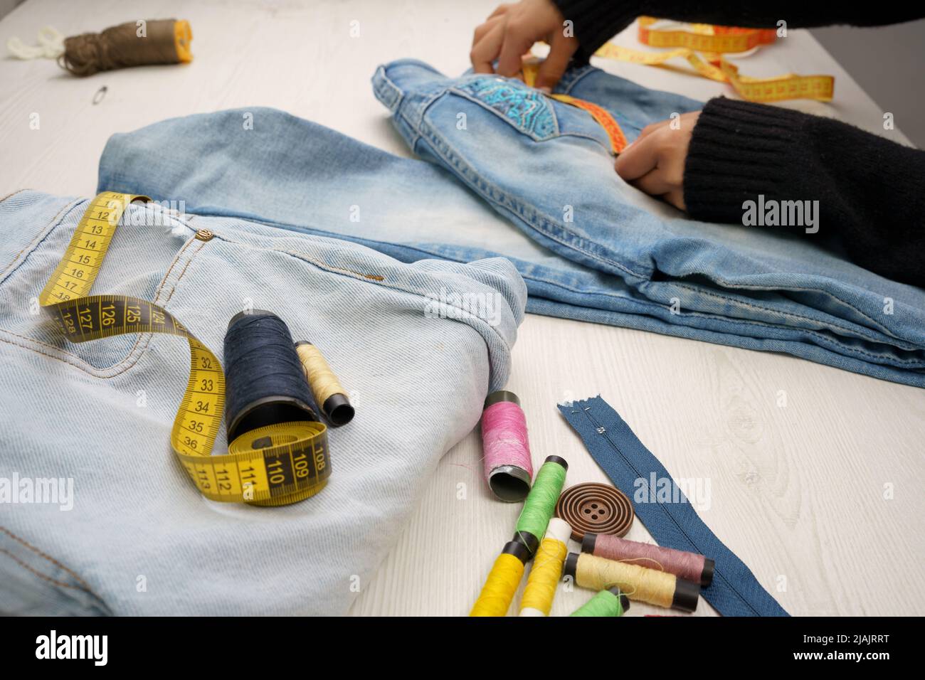 detail of a work table with hands measuring a jeans fabric with a ...