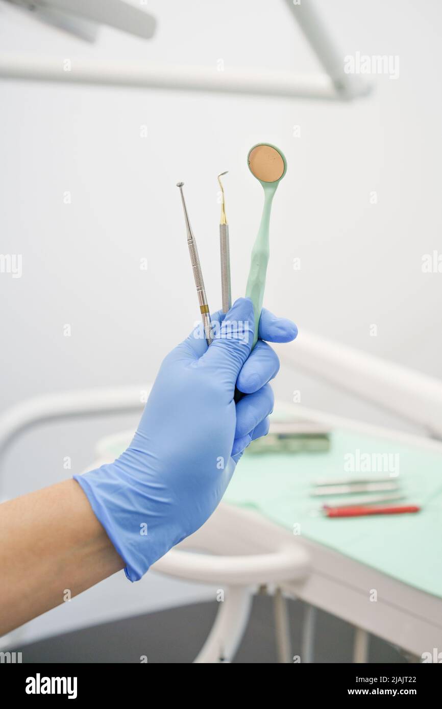 details of hand with glove holds professional dental instruments ...