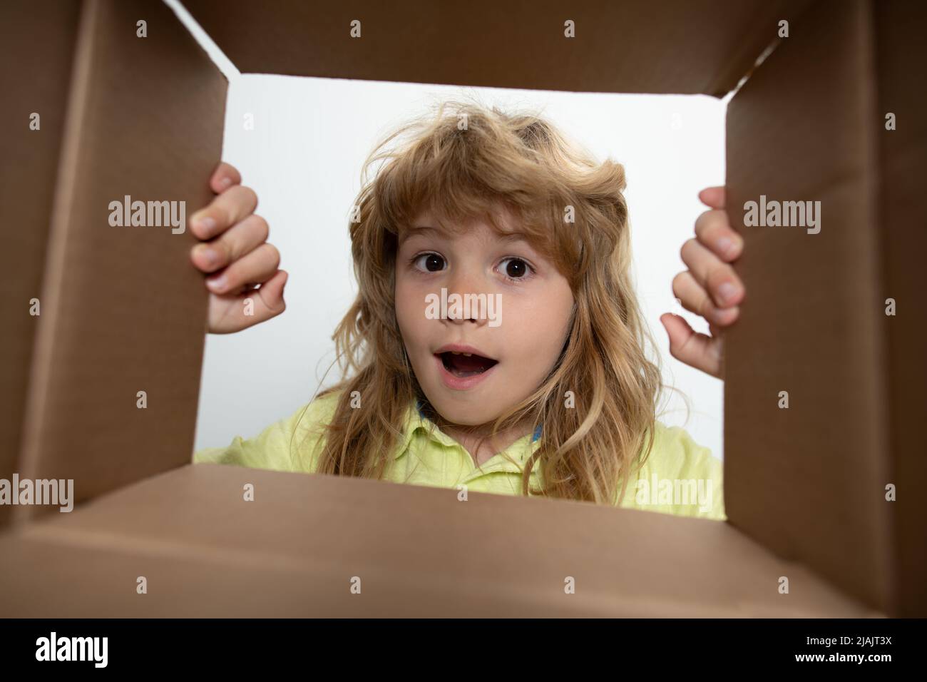 Surprised kid boy unpacking and opening carton box looking inside with ...