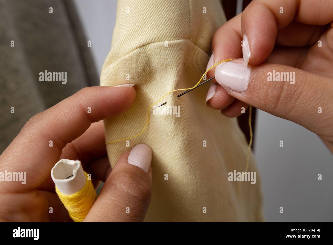 details of a seamstress's hand sewing a jacket with a needle and thread ...