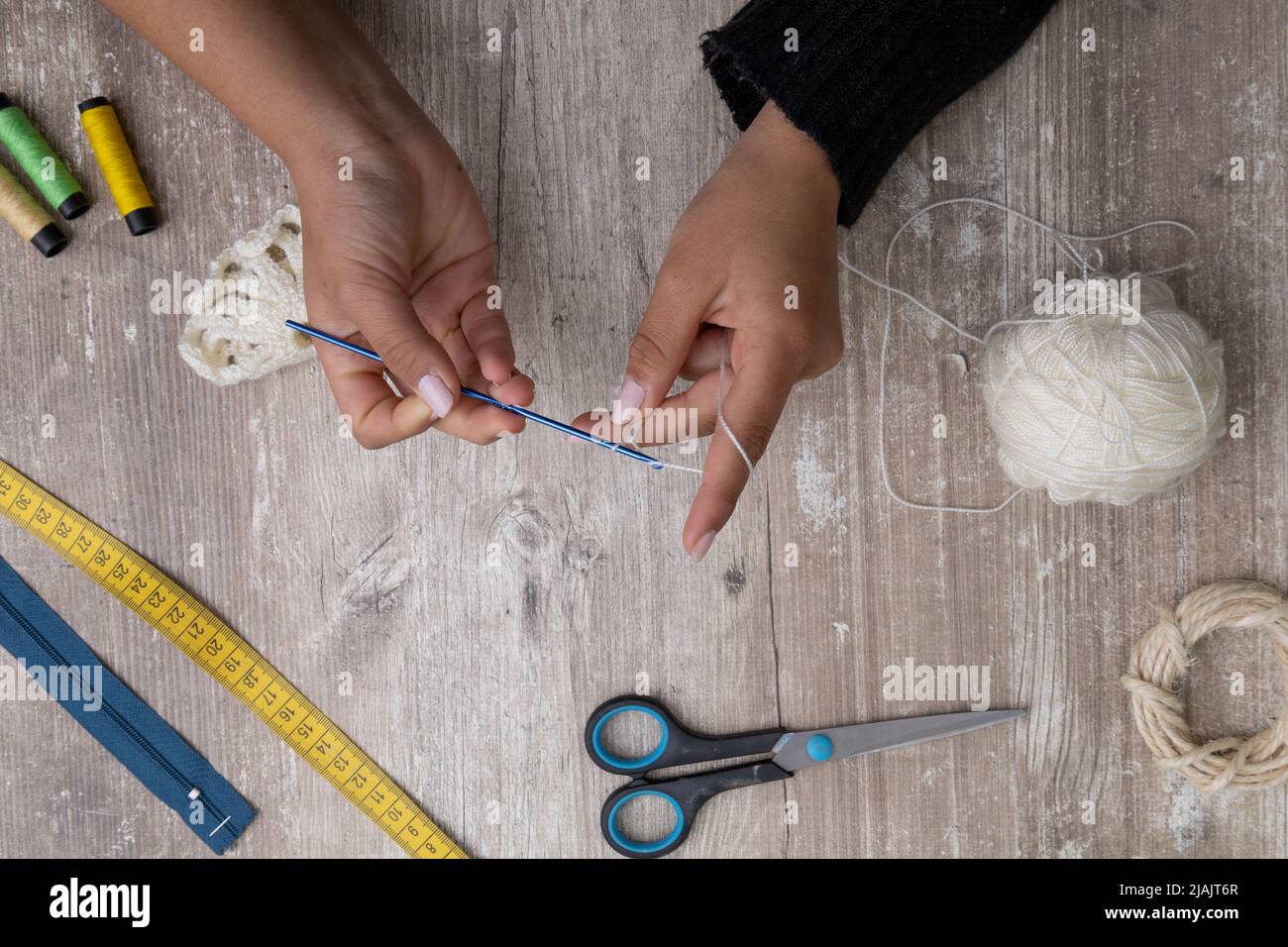 work table with tools for crafts, hands knitting with wool and crochet ...