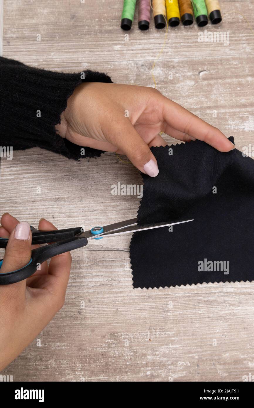 working with hands, cutting with scissors a piece of fabric to repair ...