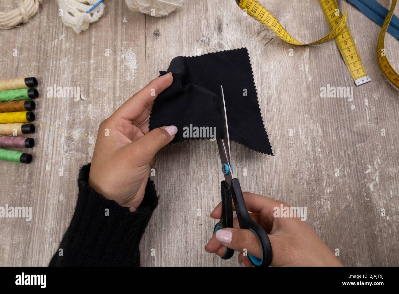 cutting with scissors a piece of black cloth to repair, sewing and art ...