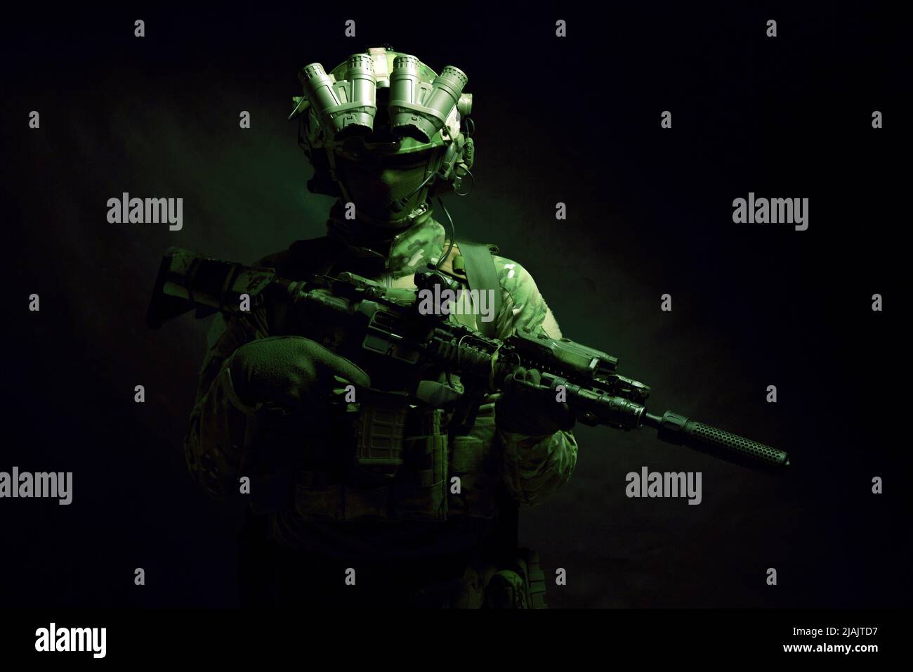 A soldier standing in darkness, equipped with night vision device and ...