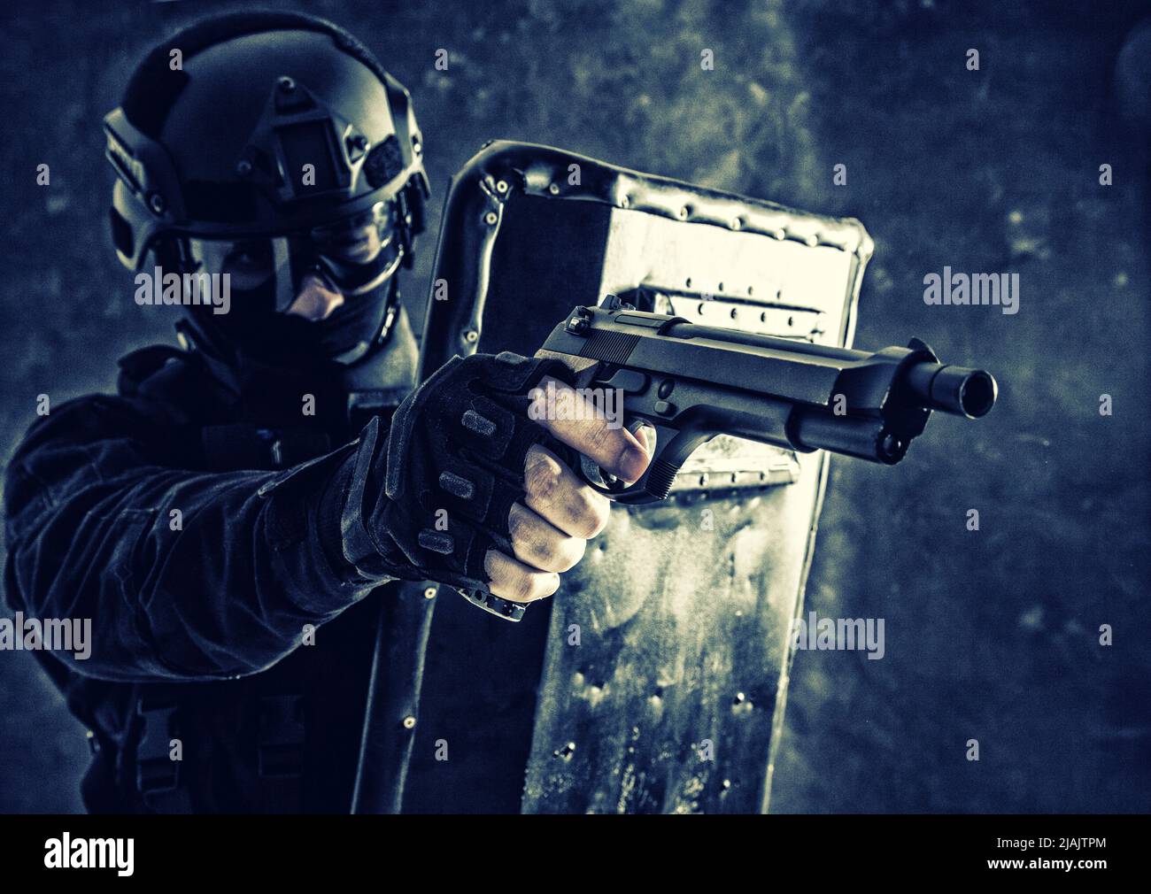 SWAT team fighter aiming pistol from behind ballistic shiield during a ...