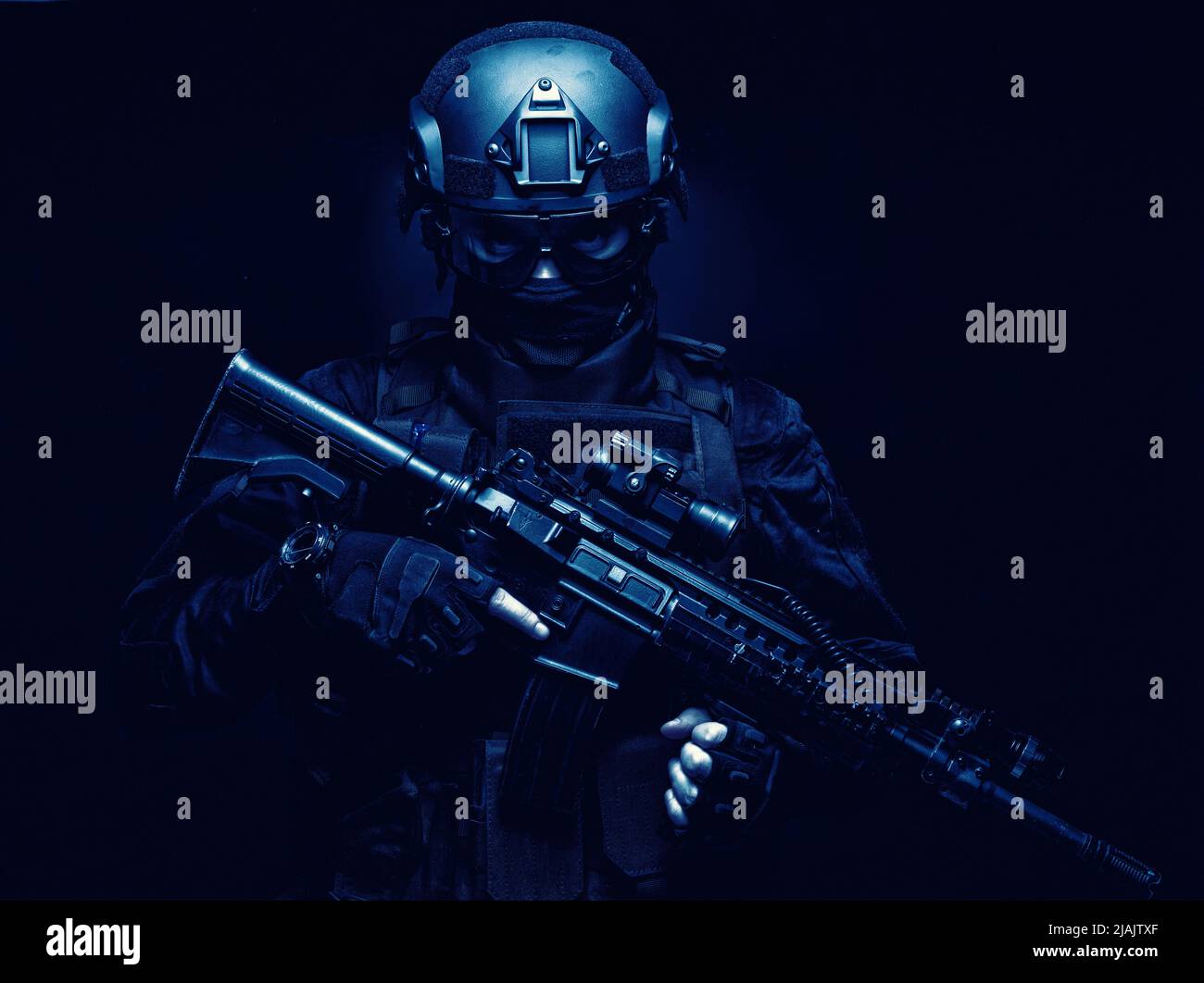 SWAT team fighter armed with assault rifle, standing in darkness, front ...