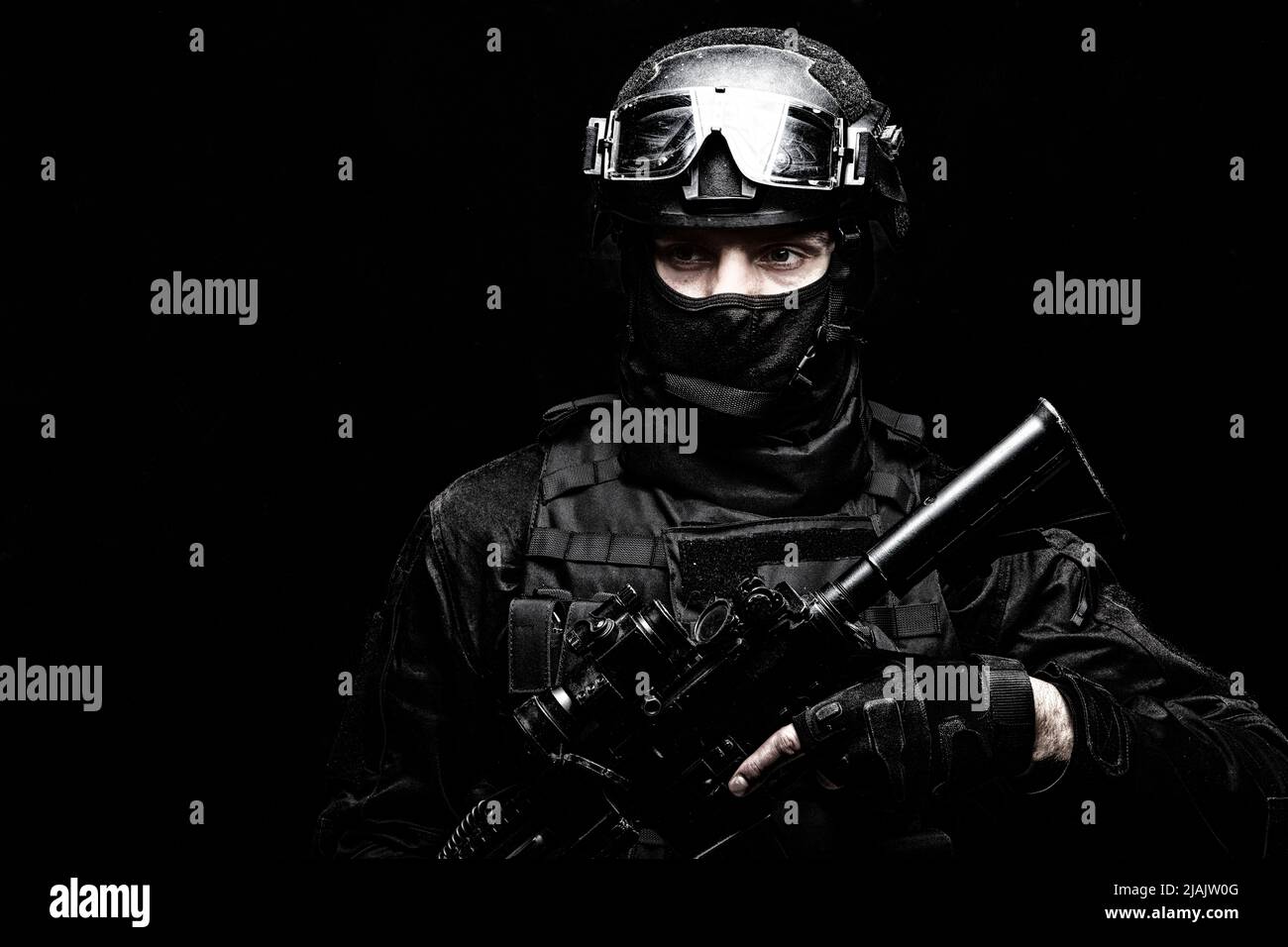 SWAT team fighter in black uniform, armed with assault rifle, studio ...