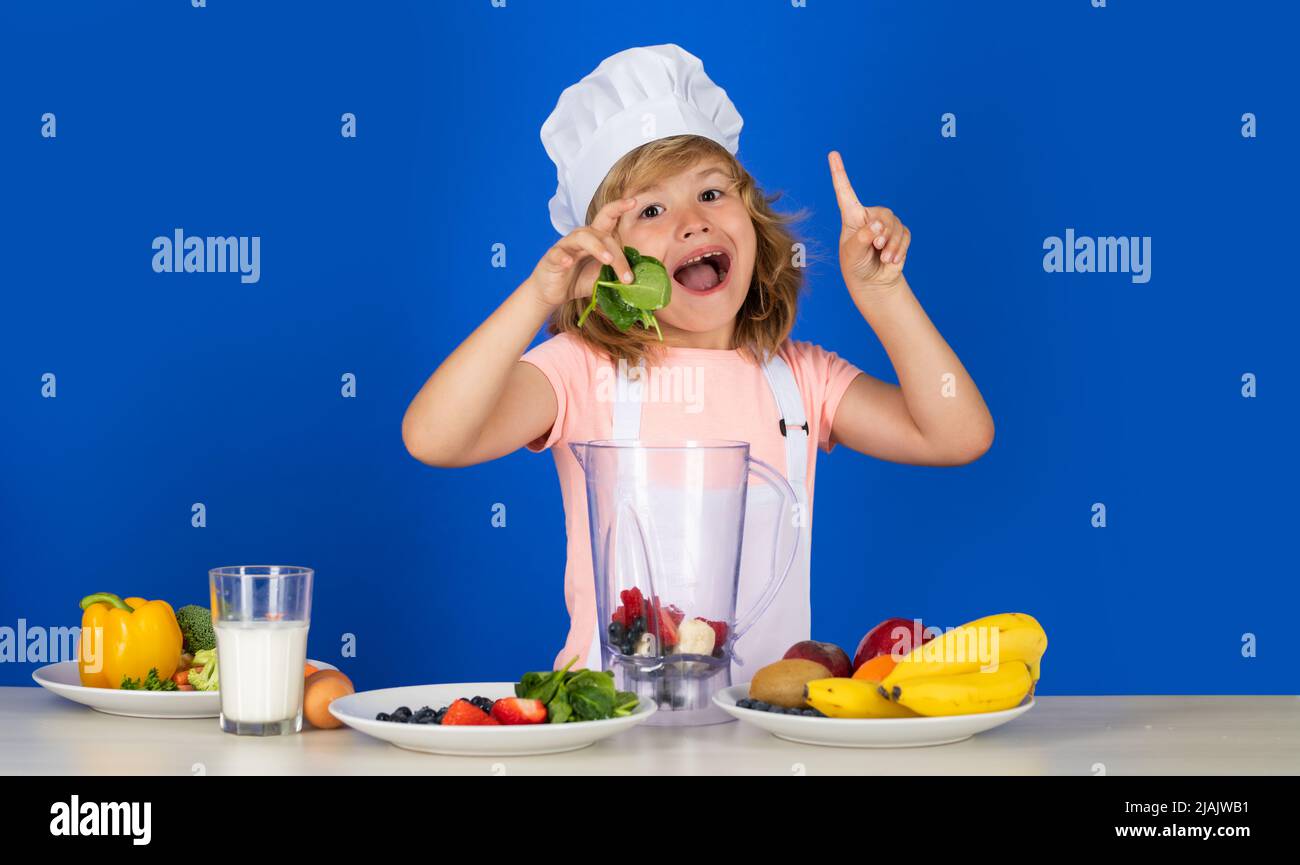 Child chef cook prepares food in isolated blue studio background. Kids ...