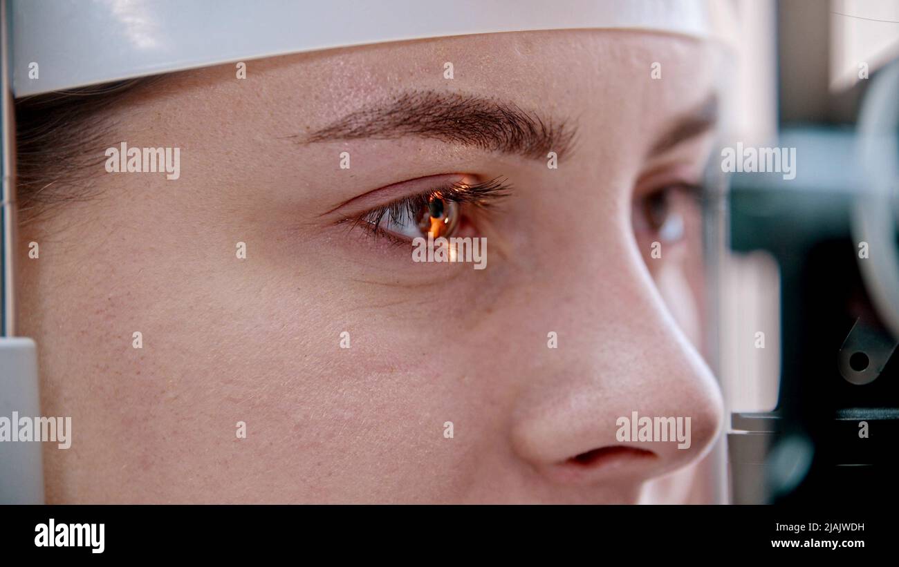 Ophthalmology treatment - a young woman with pink lips checking her visual acuity with a light ...