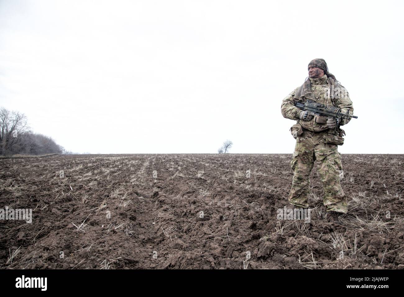Soldier standing in a muddy field with machine gun while on patrol ...