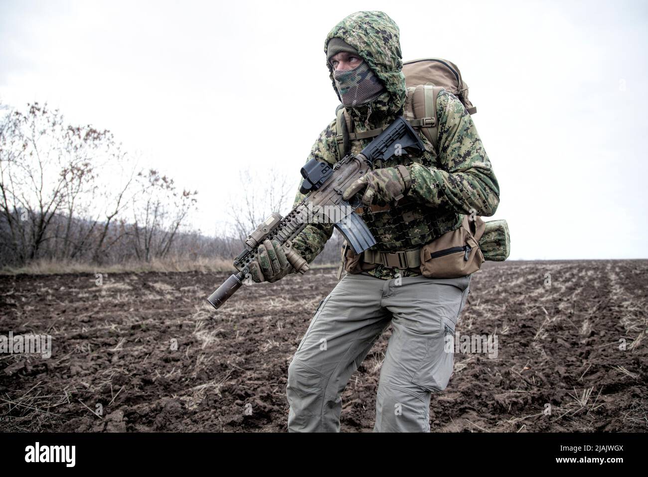 Military mercenary wearing hooded camo jacket and backpack, walking ...