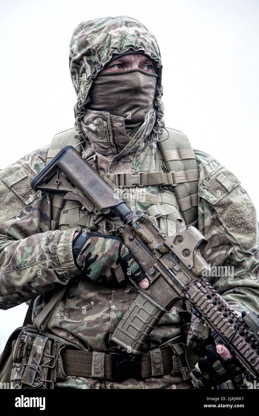 Military mercenary wearing hooded camo jacket and backpack, armed with ...