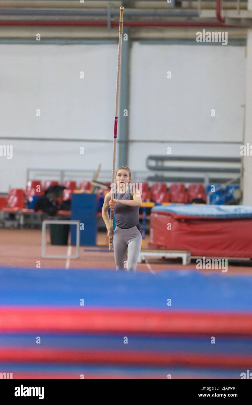 Pole vaulting indoors - young sportive woman running with a pole in the ...