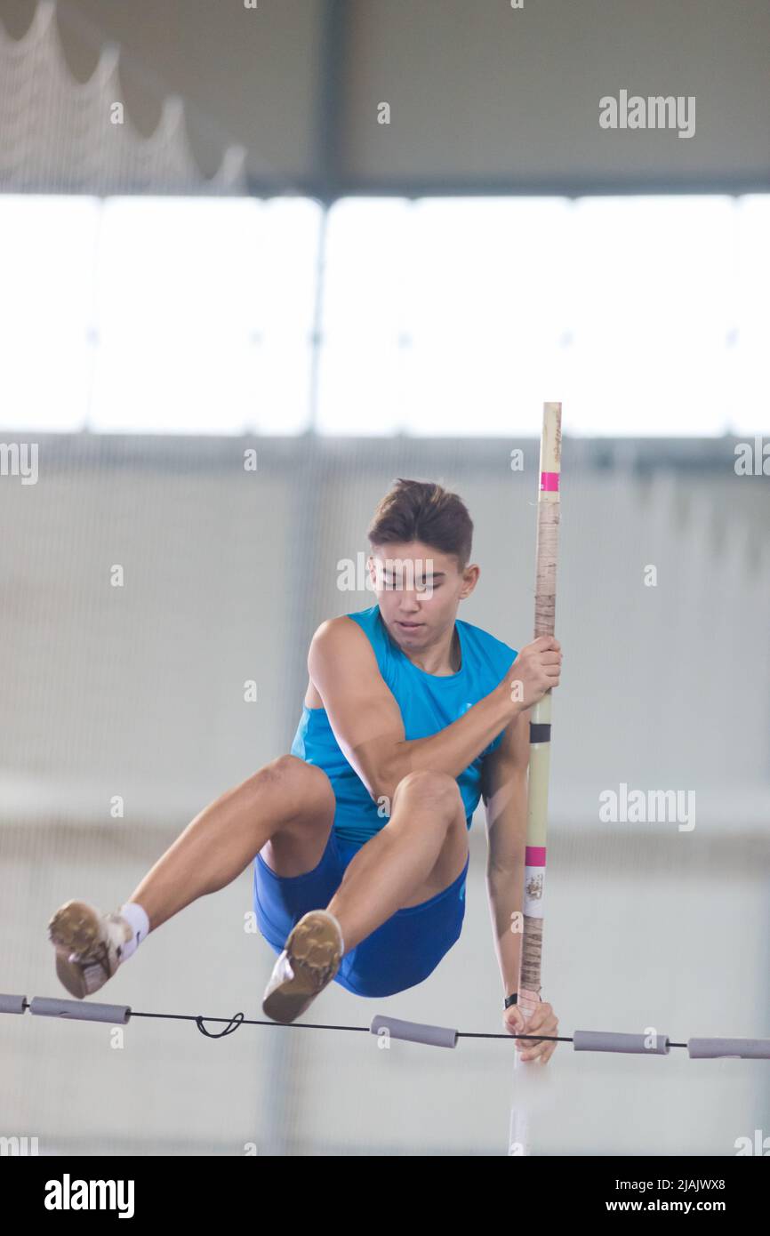 Pole vaulting indoors - young man jumping over the partition leaning on ...