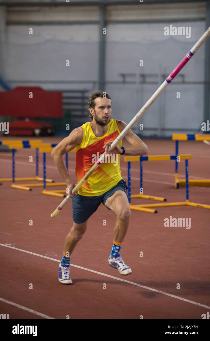 Pole vaulting indoors - a man running on the track with a pole Stock ...